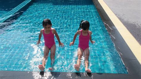 Happy Little Sisters Play In Outdoor Swimming Pool Of Tropical Resort