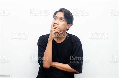 사려 깊은 아시아 남자는 붉은 배경 위에 고립된 생각 제스처로 피부를 만지는 손으로 생각하고 궁금해합니다 20 24세에 대한