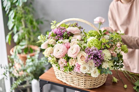 꽃 가게 컨셉 꽃집 여자는 고리 버들 바구니에 꽃꽂이를 만듭니다 혼합 꽃의 아름다운 꽃다발입니다 잘 생긴 신선한 무리입니다 꽃