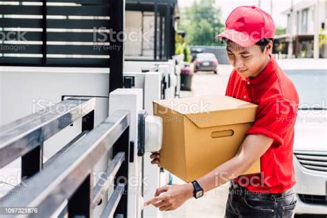행복 한 장 수 Customercourier 서비스 개념의 집 근처 서 골 판지 상자를 들고 빨간색 유니폼 나름에 대한 스톡