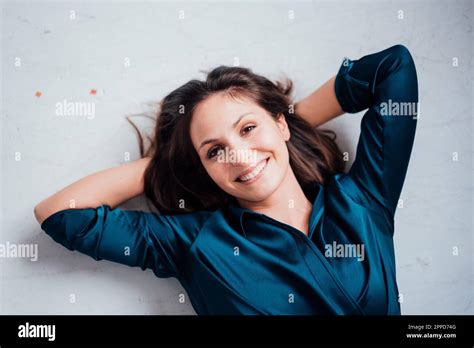 Happy Young Woman With Hands Behind Head Lying Down On Floor Stock