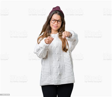격리 된 배경 펀치 주먹 싸움 공격적이 고 화가 공격 위협 및 폭력 안경 및 겨울 모자를 착용 해 젊은 아름 다운 갈색 머리