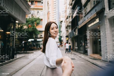 젊은 아시아 부부는 길을 선도하고 그녀의 남자 친구의 손을 잡고 여자와 도시 거리에서 걷고 사랑에 빠진다 홍콩의 현지 도시 거리에서 탐험하는 여자 친구의 손을 잡고 있는