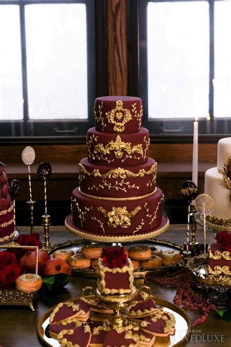 A Table Topped With Three Tiered Cakes Covered In Red And Gold Frosting