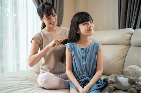 아시아를 사랑하는 어머니는 집에있는 거실에서 어린 소녀 딸과 여가 시간을 보냅니다 돌보는 엄마는 부드러운 헤어 브러시와 작은