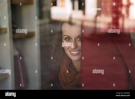 Captivating Smile Of A Young Woman With Curly Hair Seen Through A Cafe