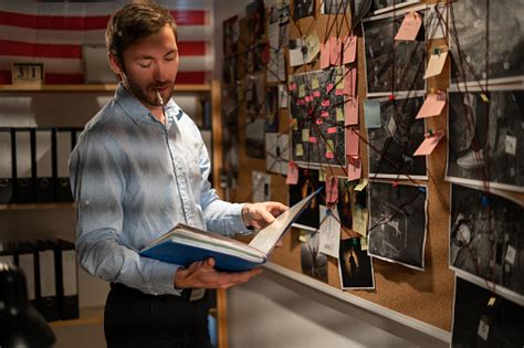 검은 양복을 입은 젊은 형사가 어두운 사무실에서 서류를 읽고 있다 형사 사건 문서를 다루는 수사관 널판지에 대한 스톡 사진 및 기타 이미지 Istock