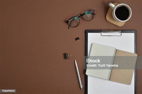빈 클립 보드 사무 용품 펜 커피 컵 메모장 및 갈색 배경에 안경 작업 공간을 모의 플랫 레이 평면도 복사 공간 0명에 대한