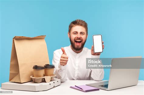 흰색 스크린 스마트 폰 커피 피자 및 종이 봉투를 들고 엄지 손가락을 보여주는 행복한 만족 남성 클라이언트는 테이블 온라인 주문