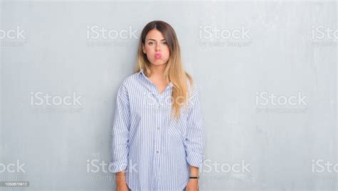 재미 있은 얼굴 뺨 피 패션 비즈니스 옷을 입고 회색 그런 지 벽에 젊은 성인 여자 입 어 미친 식으로 팽창 가득 찬에 대한