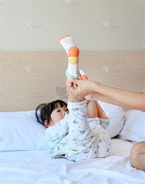 妈妈试着给女儿在床上放一只袜子。
