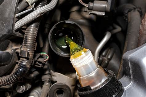 Un mecánico de automóviles vierte aceite nuevo en el motor desde un tanque de plástico en un