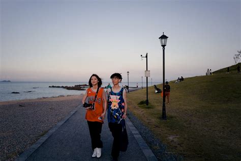 낮 동안 회색 콘크리트 도로에 서 있는 주황색 재킷을 입은 여자 사진 Unsplash의 무료 램프 포스트 이미지