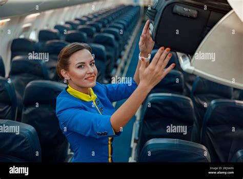 Stewardess Putting Travel Bag In Overhead Luggage Shelf In Airplane