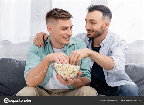 Cheerful Same Sex Couple Looking Each Other While Reaching Popcorn