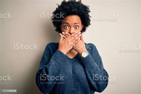 젊은 아름 다운 아프리카 계 미국인 Afro 여자 곱슬 머리 캐주얼 스웨터를 입고 실수로 손으로 입을 덮는 충격 비밀 개념입니다