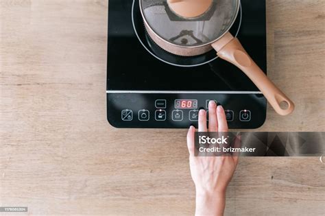 제어판이 있는 작은 전기 스토브에서 젊은 성인 여성의 선택 프로그램 주방에서 복사 공간이있는 나무 테이블 위에 가전 제품에서