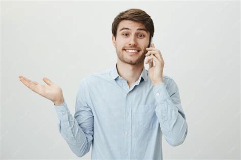 Clueless Cute Man With Bristle Talking On Phone And Shrugging Free Photo