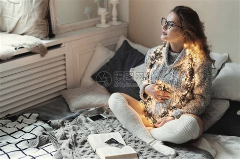迷人的怀孕年轻女子盘腿坐在床上放松高清图片下载 正版图片505799381 摄图网