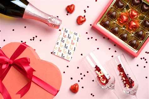 발렌타인 데이 플랫 평신기 구성 초콜릿 하트 모양의 기프트 박스 샴페인 병과 안경 인사말 카드 와 분홍색 테이블에 색종이의 상단