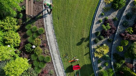 Aerial View Of Gardener Blowing Dirt And Leafs From Garden Cobble Paths