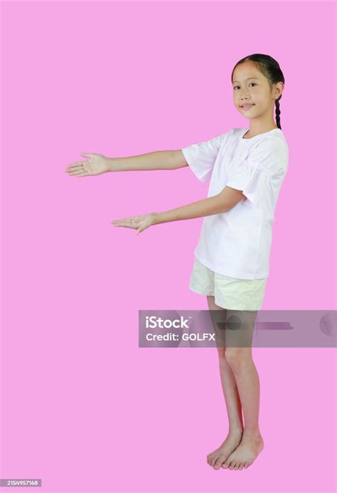 미소 짓는 아시아 소녀 아이는 분홍색 스튜디오 배경에 고립 된 복사 공간에 뭔가를 제시 서 있습니다 클리핑 패스가 있는 이미지 전체 길이입니다 8 9 살에 대한 스톡 사진