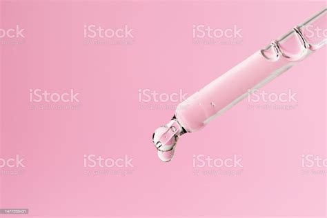 분홍색 배경에 떨어지는 얼굴 혈청이 있는 유리 피펫 거품이 있는 액체 스킨 케어 화장품 근접 촬영 에센셜 오일 방울 매크로 스포