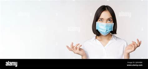 Annoyed Asian Woman In Medical Face Mask Shrugging And Looking Up With Bothered Face Expression