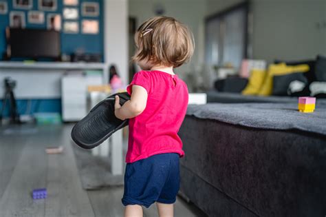 방에서 혼자 집에서 슬리퍼를 가지고 노는 한 백인 유아 소녀 아이는 자라나는 공간과 어린 시절 발달 개념 백뷰를 복사합니다 12 17 개월에 대한 스톡 사진 및 기타 이미지