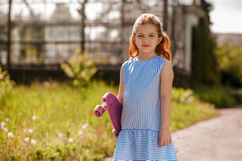 Premium Photo Cute Ginger Girl With A Skateboard In Hands