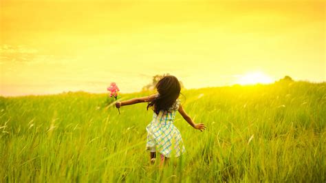Обои на рабочий стол Девочка с цветком в руке бежит по лугу обои для рабочего стола скачать