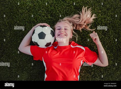Portrait Of Smiling Girl Football Player With Soccer Ball Lying On The