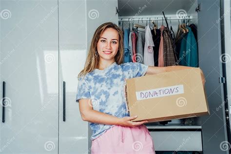 Smiling Woman With Box Of Selected Clothes From Her Wardrobe For