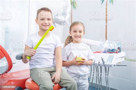 치과 의사의 사무실에서 어린 소년과 소녀 아이들은 치과 의사를 놀고 칫솔과 사과를 손에 들고 있습니다 개념은 아이들의 치아의