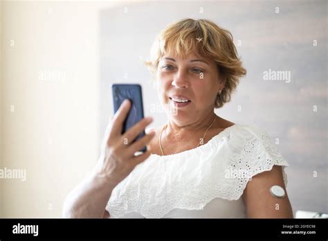 Woman Testing Glucose Level With Continuous Glucose Monitor On Mobile Phone Stock Photo Alamy