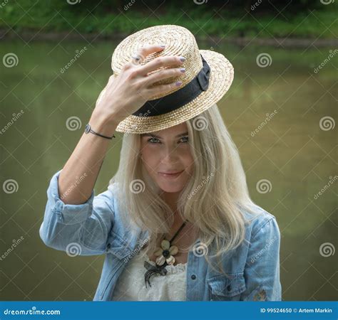The Blonde Is Holding A Straw Hat On Her Hand And Smiling At The Camera