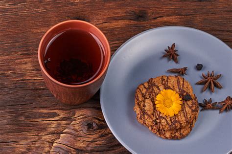 홍차와 검은 배경에 나무 테이블 위에 노란 꽃과 초콜릿 Coockies의 컵 0명에 대한 스톡 사진 및 기타 이미지 0명