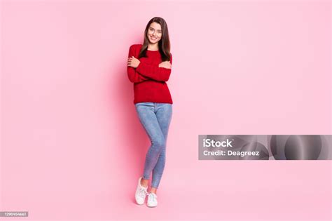 매력적인 소녀포옹 어깨 빛나는 화이트 스마일 착용 레드 풀오버 데님 청바지 운동화 고립 된 핑크 컬러 배경 갈색 머리에 대한