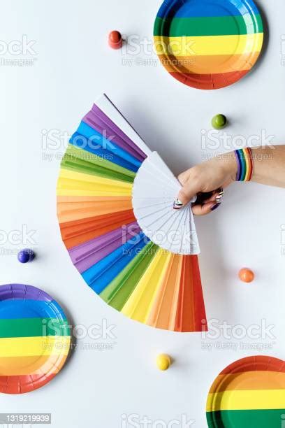 Lgbtq 커뮤니티 자부심 달 무지개 개념 플랫 레이 리본이 있는 손 무지개 팬 종이 접시와 빨대를 마십니다 평면 평지 흰색