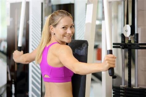 Sporty Blonde Woman At The Gym Doing Exercises On A Training Machine