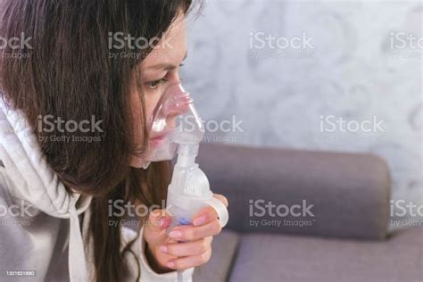 치료에 분무기와 흡입기를 사용합니다 흡입기 마스크를 통해 흡입 하는 젊은 여자 얼굴 클로즈업 측면 보기 30 34세에 대한 스톡