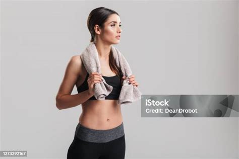 스포츠웨어에 수건으로 포즈를 취하고 체육관에서 옆으로 바라보며 회색 배경을 통해 고립된 잘 지어진 피트니스 여성의 사진 강사에 대한 스톡 사진 및 기타 이미지 Istock