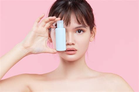 뷰티 우먼 얼굴입니다 손에 크림 한 병을 들고 신선한 피부와 젊은 아시아 여자의 닫습니다 여자 눈 아래 크림 병 템플릿 화장품을 적용 Mockup 스킨 케어 컨셉 건강관리와