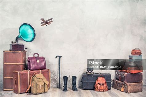 빈티지 클래식 골동품 가방 오래된 트렁크 수하물 배낭 가죽 부츠 실린더 모자 축음기 및 장난감 비행기 앞 콘크리트 벽 배경 여행 수하물 개념 복고풍 스타일 필터링 사진 0