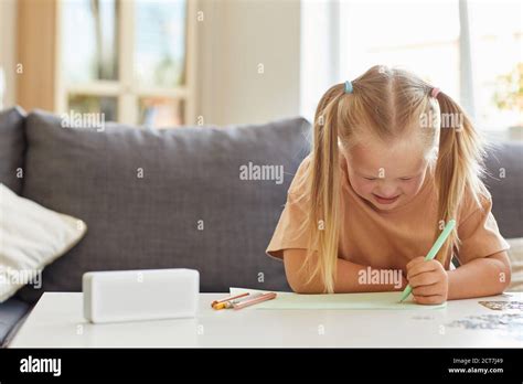 Vue de face à la petite fille mignonne avec le syndrome de Down dessin des images pendant les