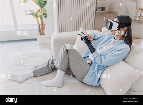 Relaxed Young Woman With A Prosthetic Arm Enjoys A Virtual Reality Experience Comfortably