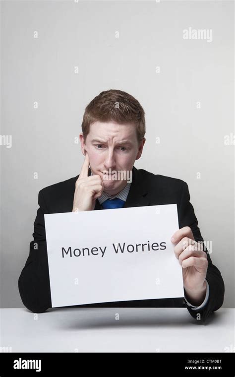 Man In A Suit Sat At A Desk Look At A Piece Of Paper With The Words