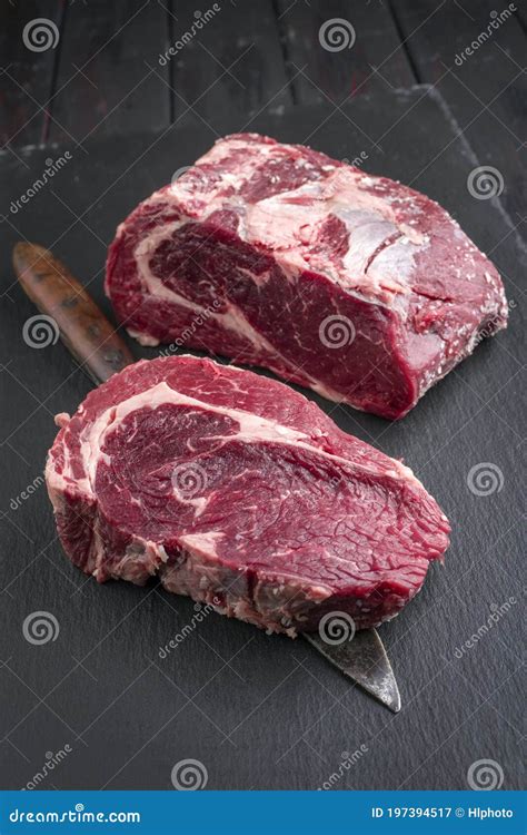 Raw Dry Aged Angus Entrecote Beef Steak And Roast On A Black Board