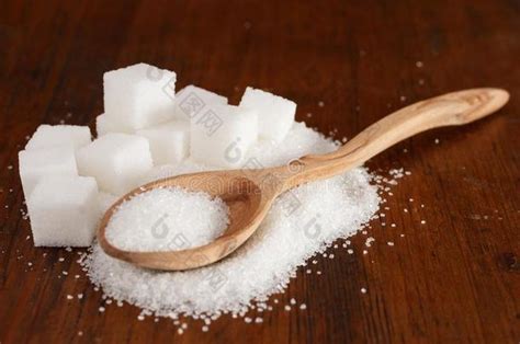 颗粒状的食糖采用木制的勺和立方形隔离的向图片 包图网企业站