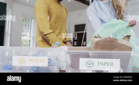 Midsection Of Diverse Couple Segregating Plastic Bottles And Paper At